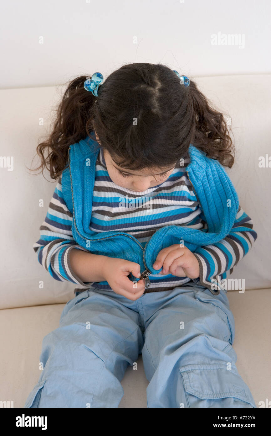 Little girl is trying to close the zipper of her jacket Stock Photo - Alamy