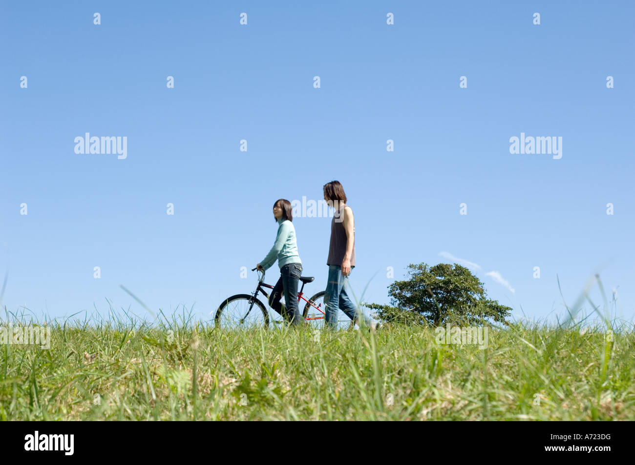 Young couple walking, woman pushing bicycle Stock Photo - Alamy