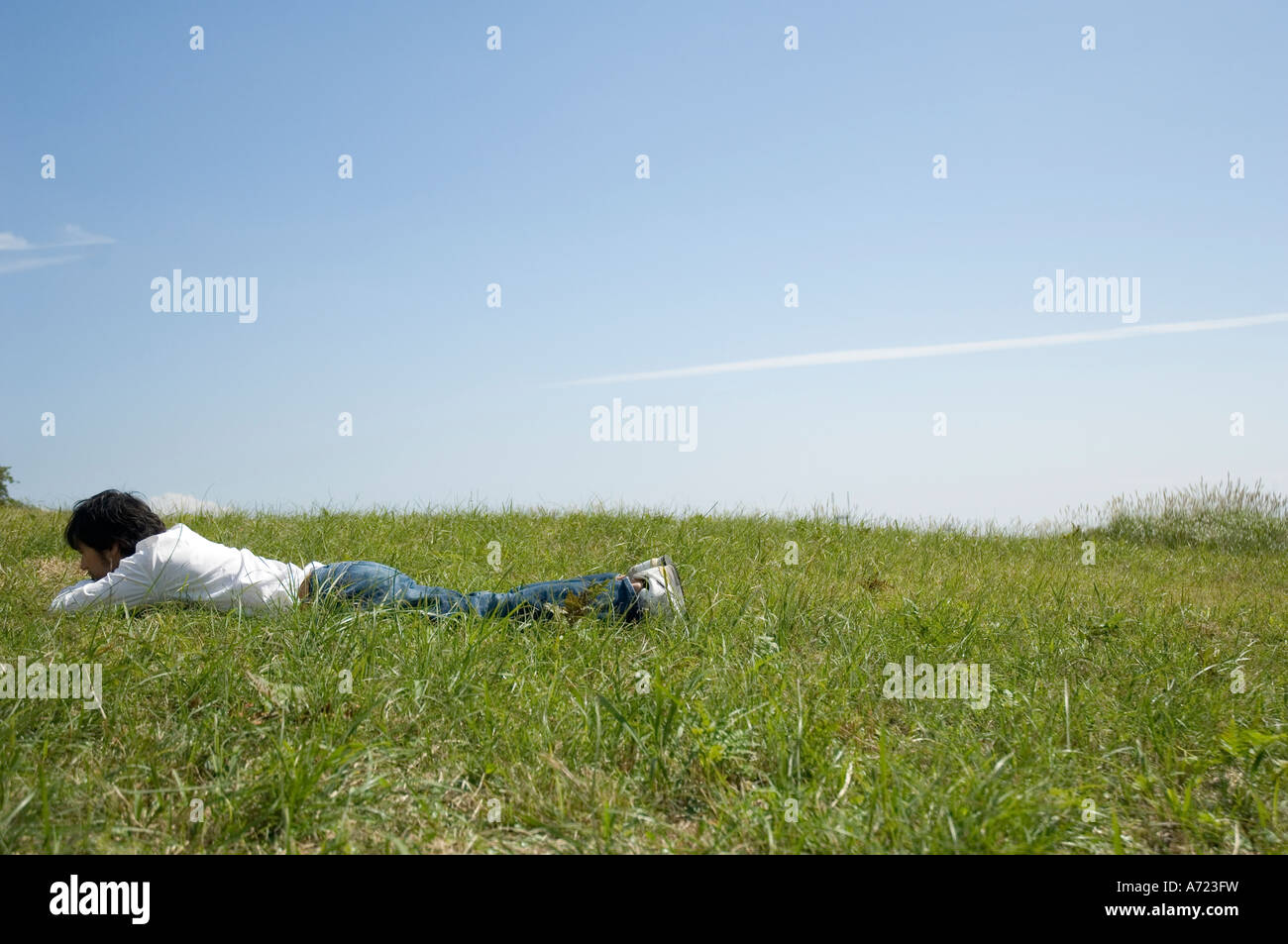 Young man lying down on field Stock Photo - Alamy