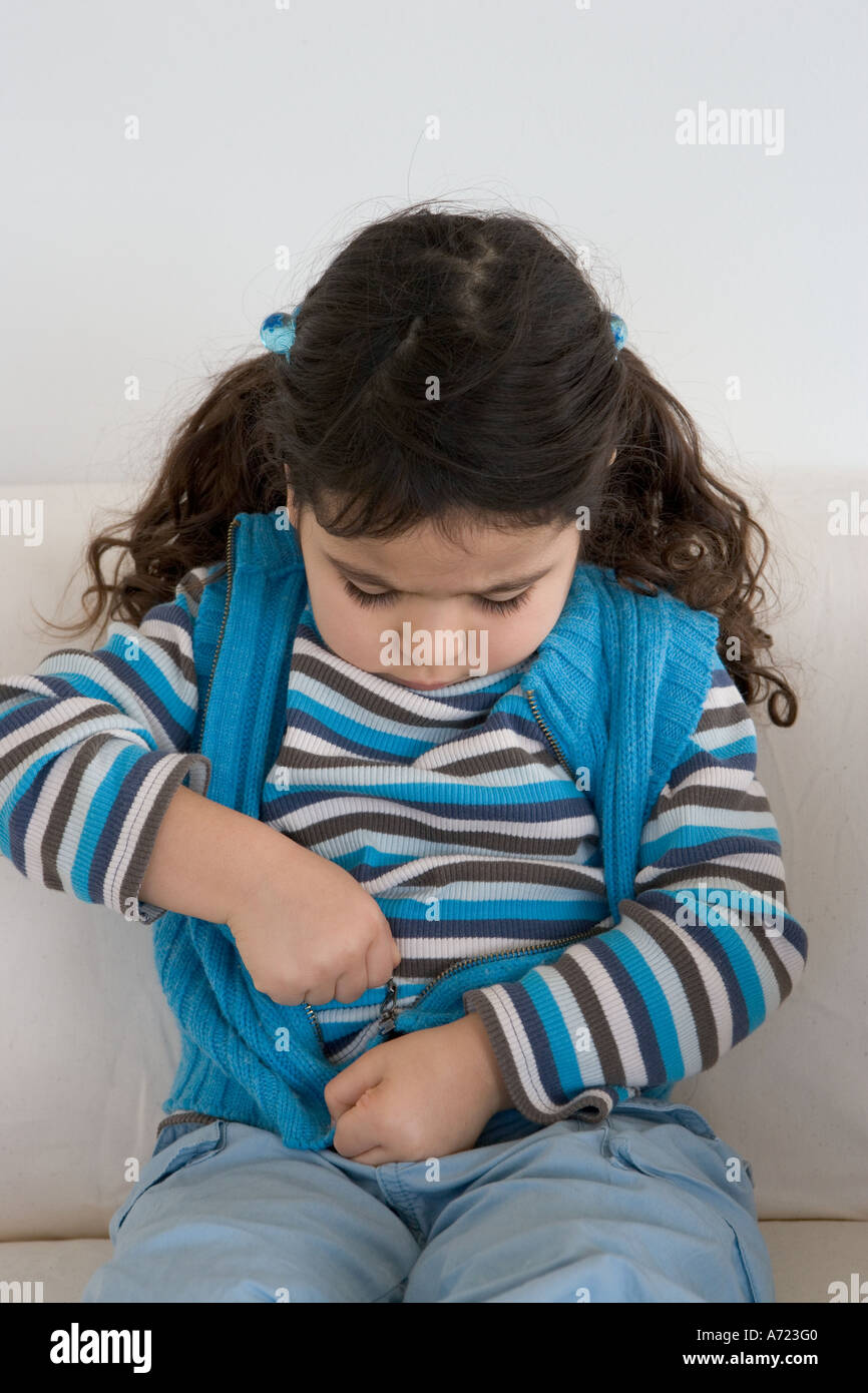 Little girl is trying to close the zipper of her jacket Stock Photo - Alamy