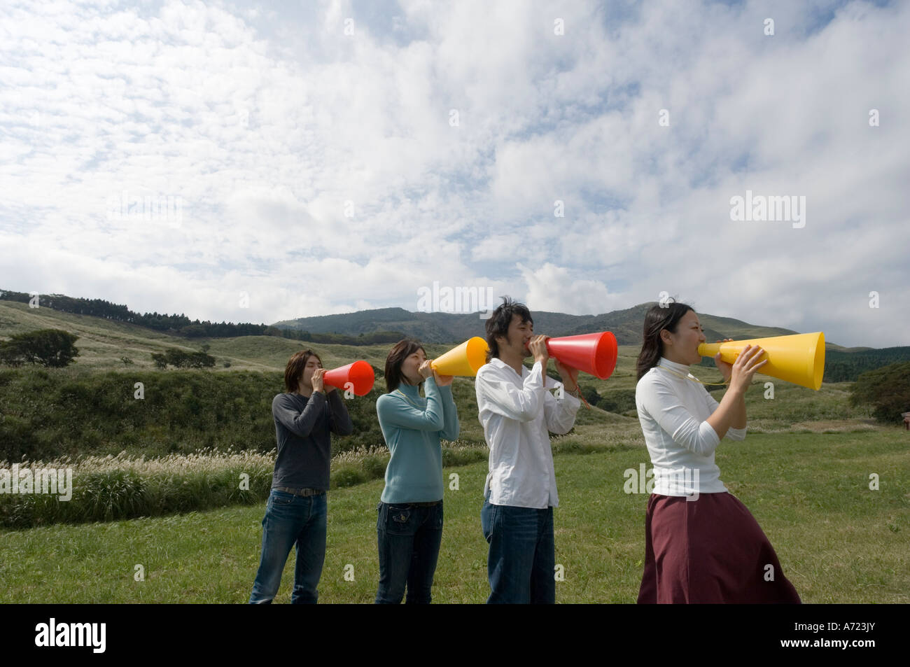 Four young people shouting into megaphones Stock Photo - Alamy