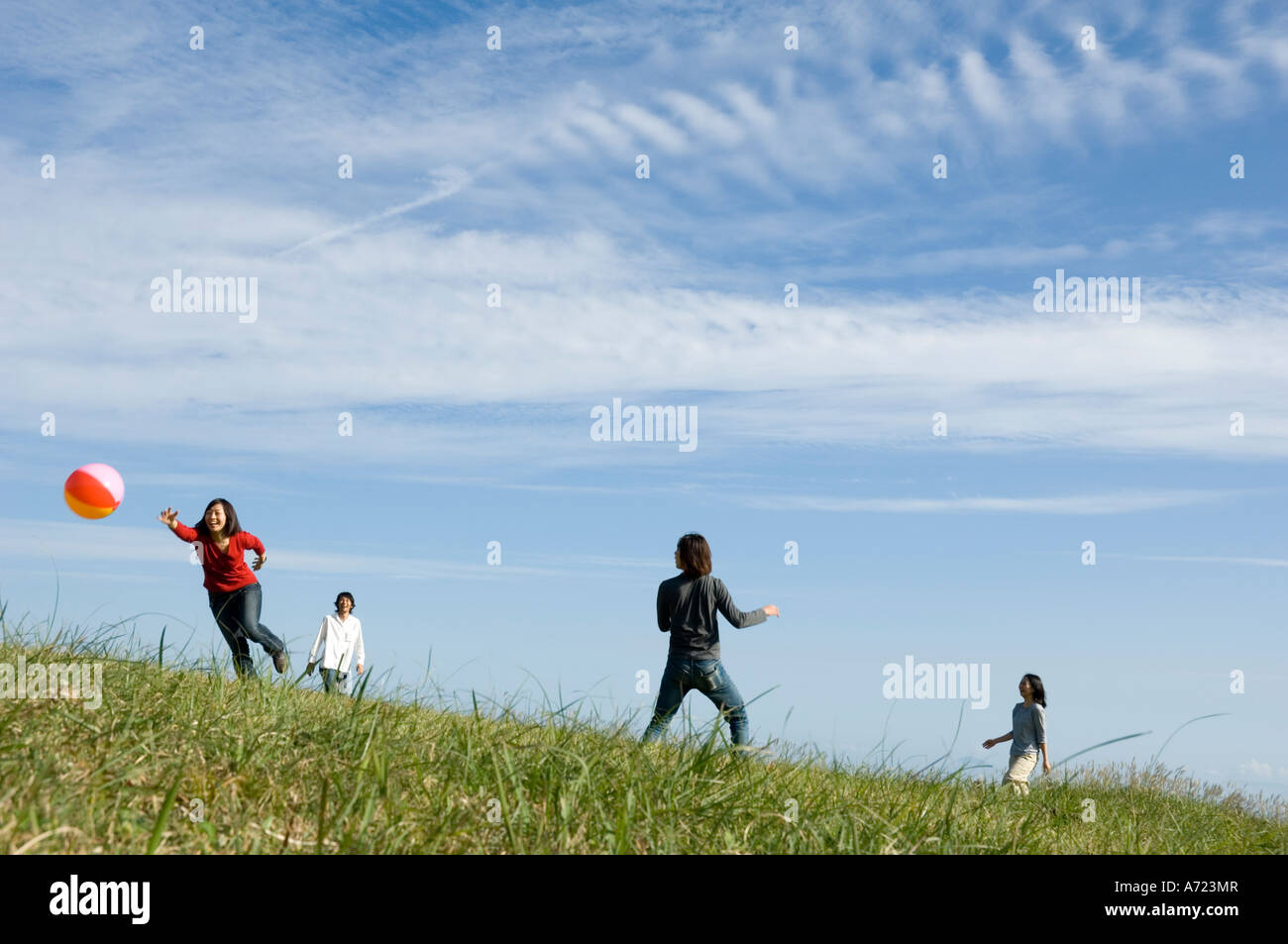 Four young people playing with beach ball Stock Photo - Alamy
