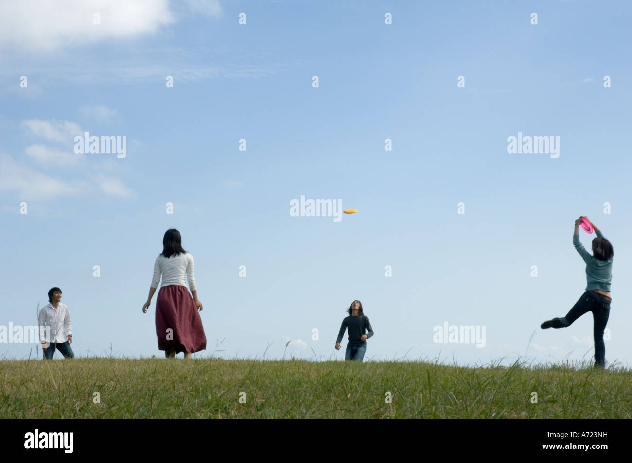 Four young people playing with flying disc Stock Photo - Alamy