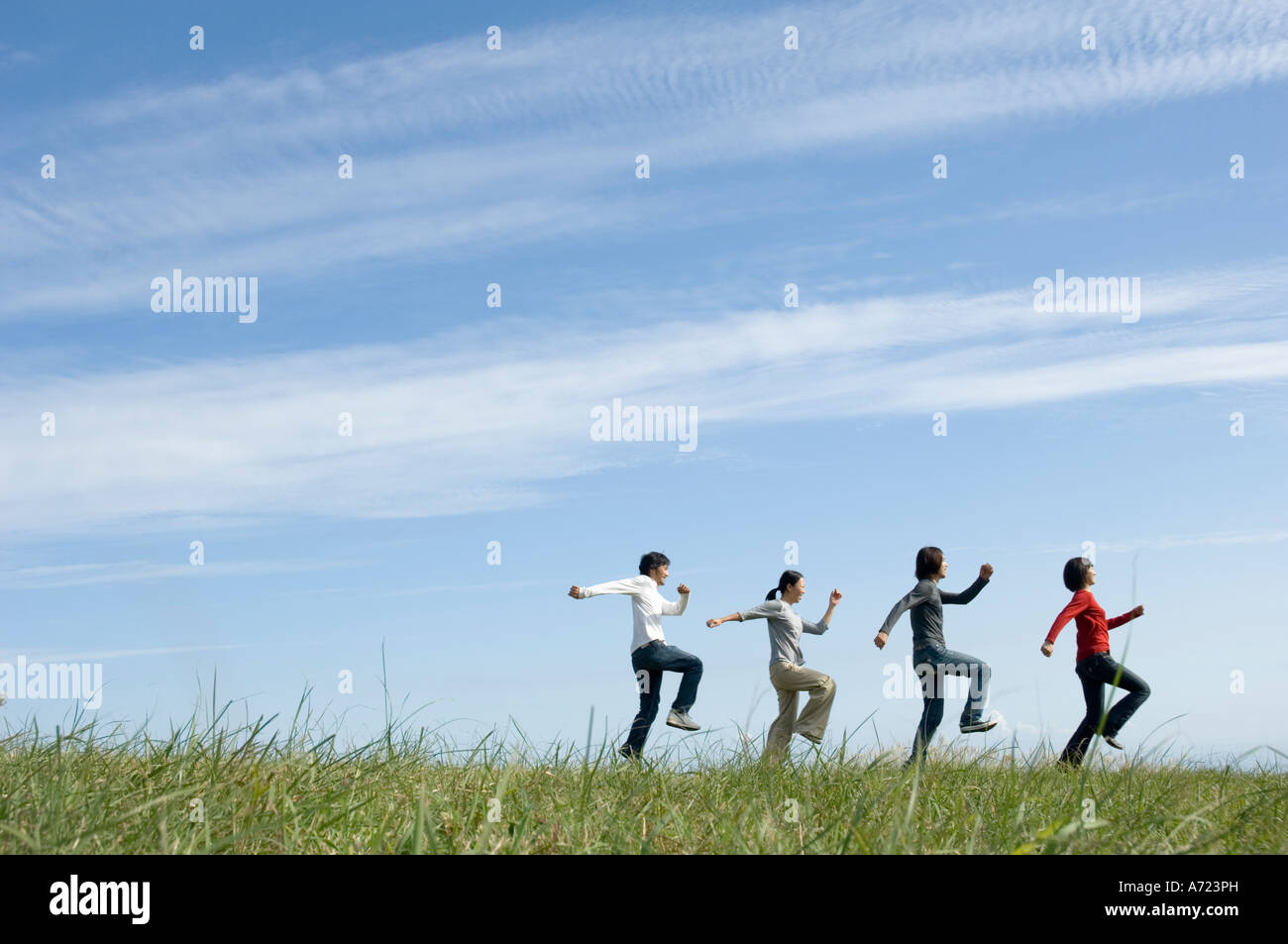 Four young people skipping in field Stock Photo - Alamy