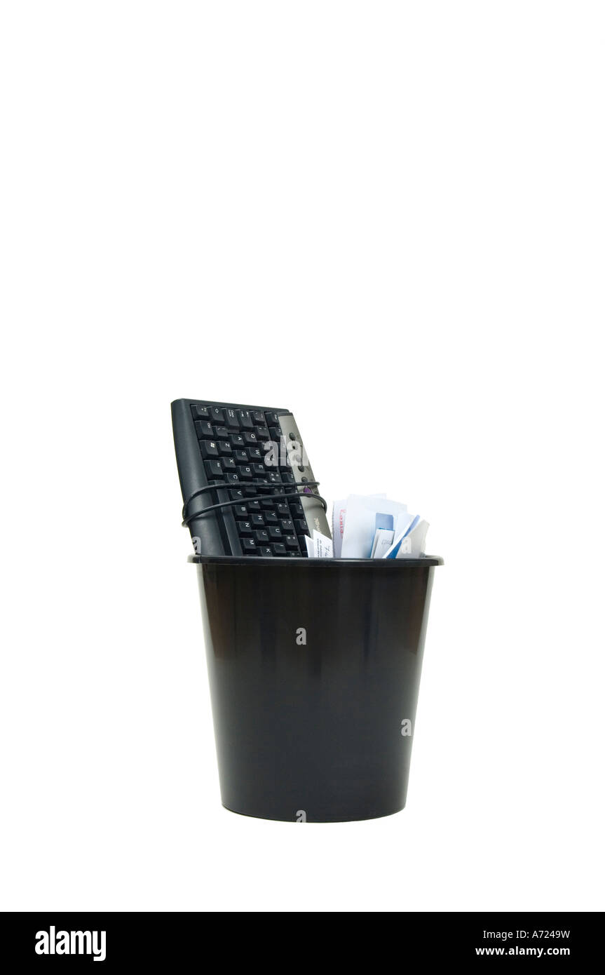 A discarded computer keyboard in a black bin with office stationery ...