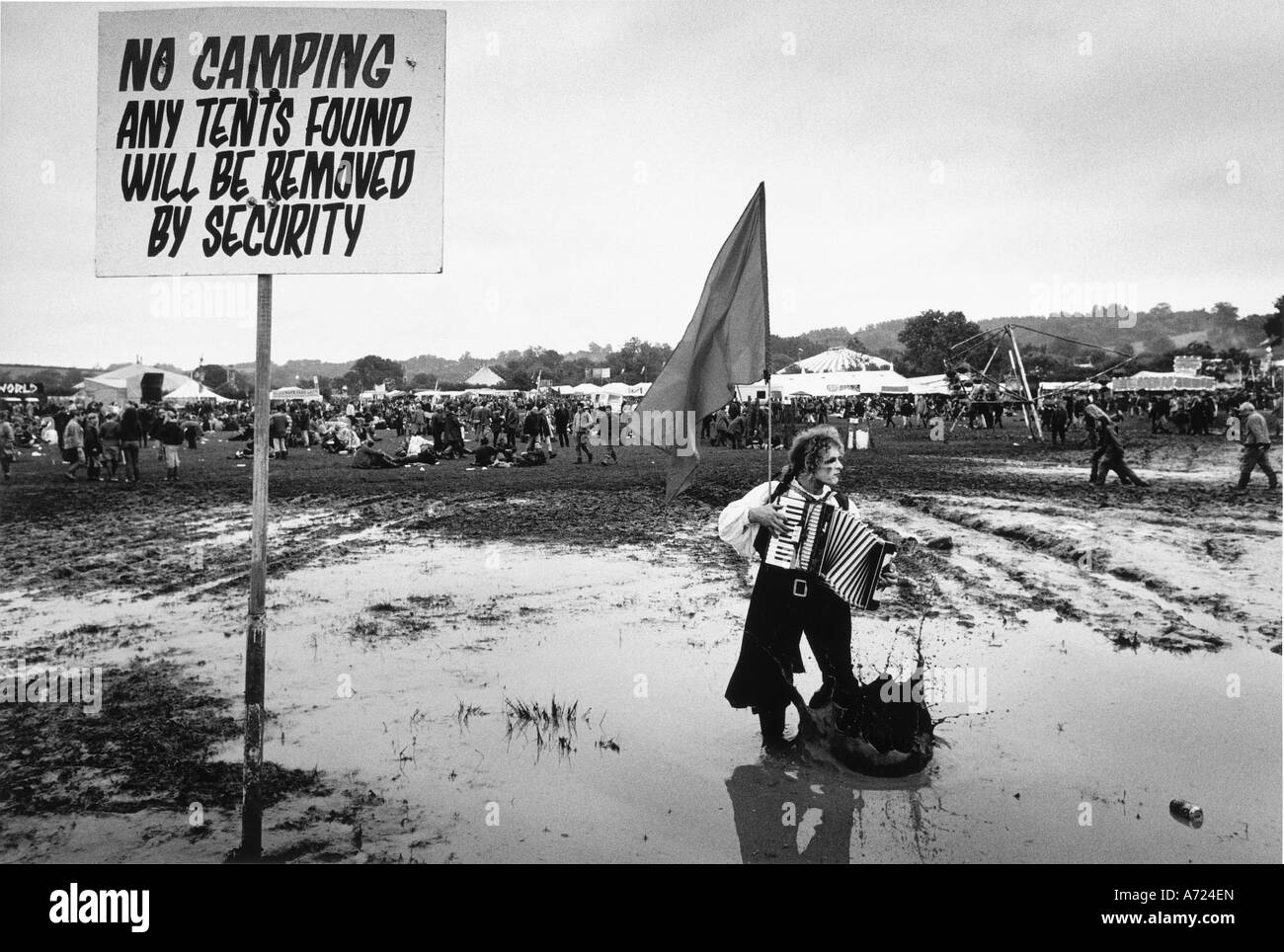 A wandering accordion player stamps his foot in the mud as he plays ...