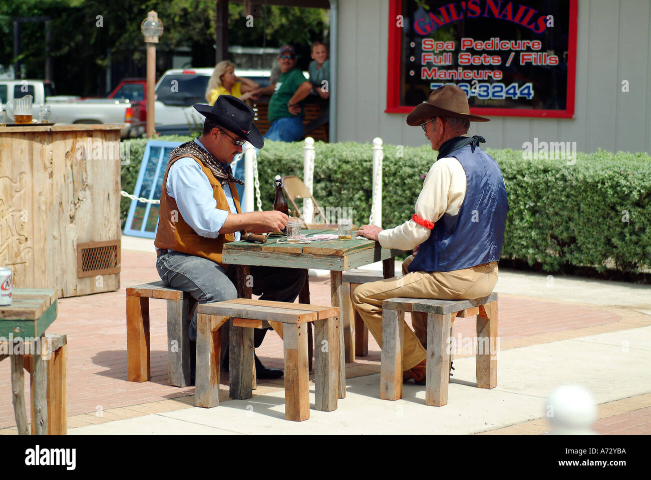 Two cowboys actors playing card sitting around table Stock Photo - Alamy