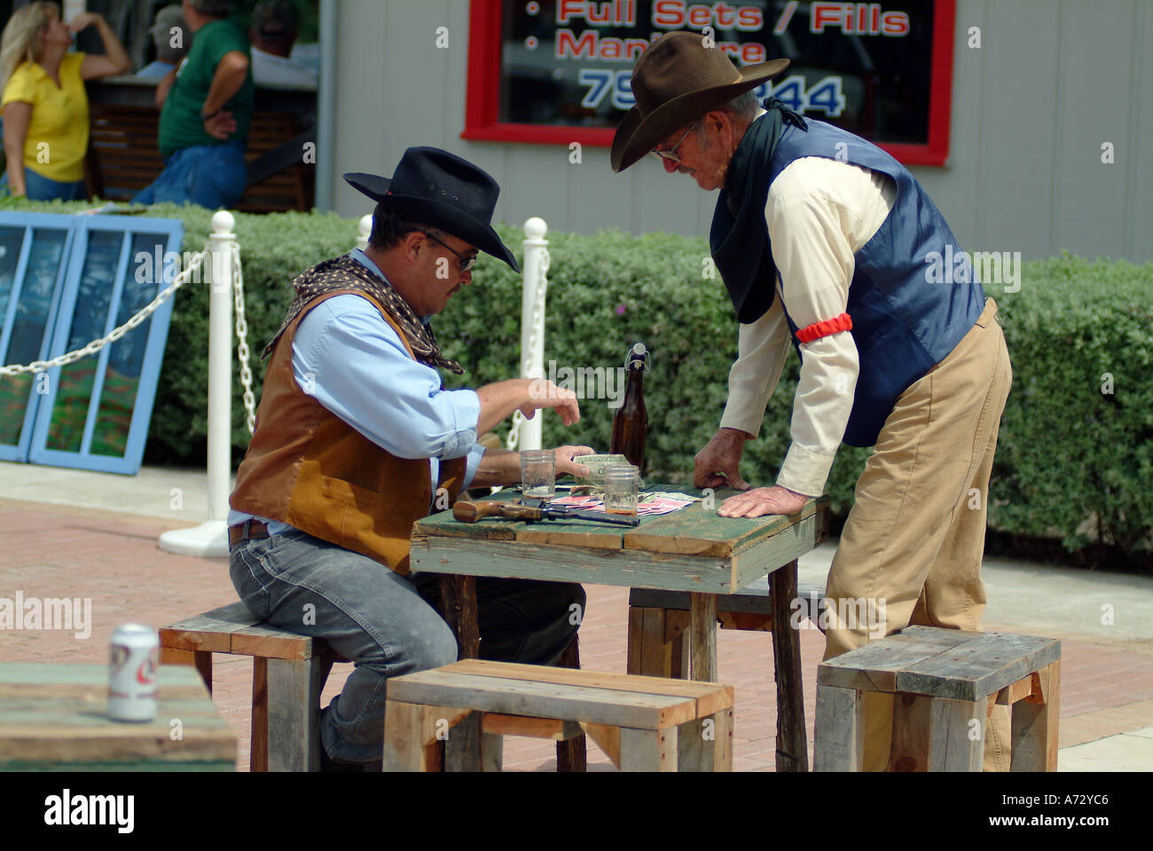 Two cowboys actors playing card sitting around a wood table Stock Photo ...