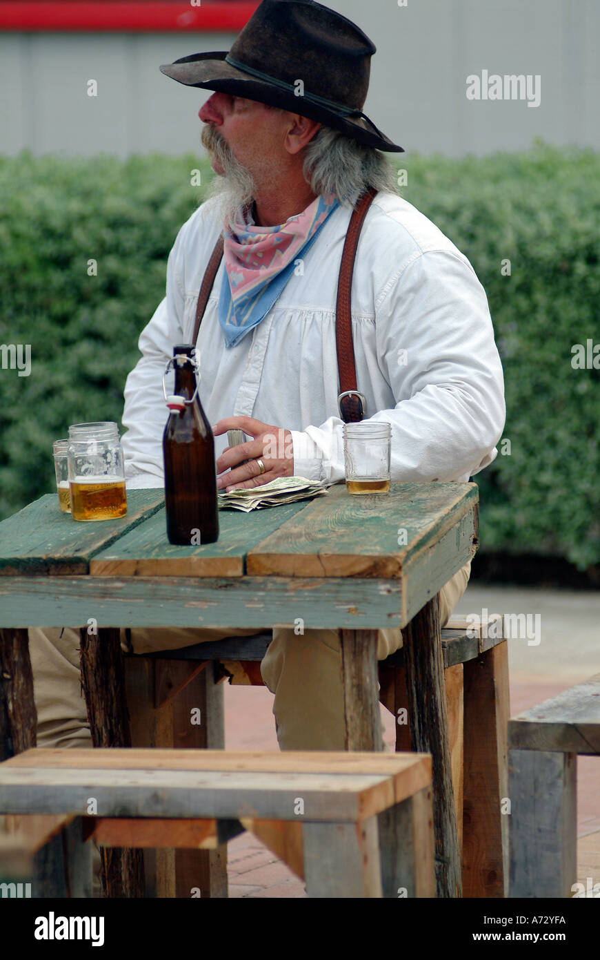 A man acting a cowboy playing card around a table Stock Photo - Alamy