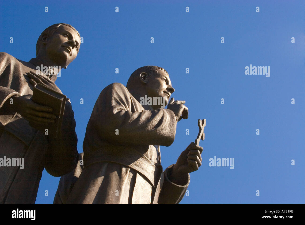 Statue of two men holding cross and book Stock Photo - Alamy