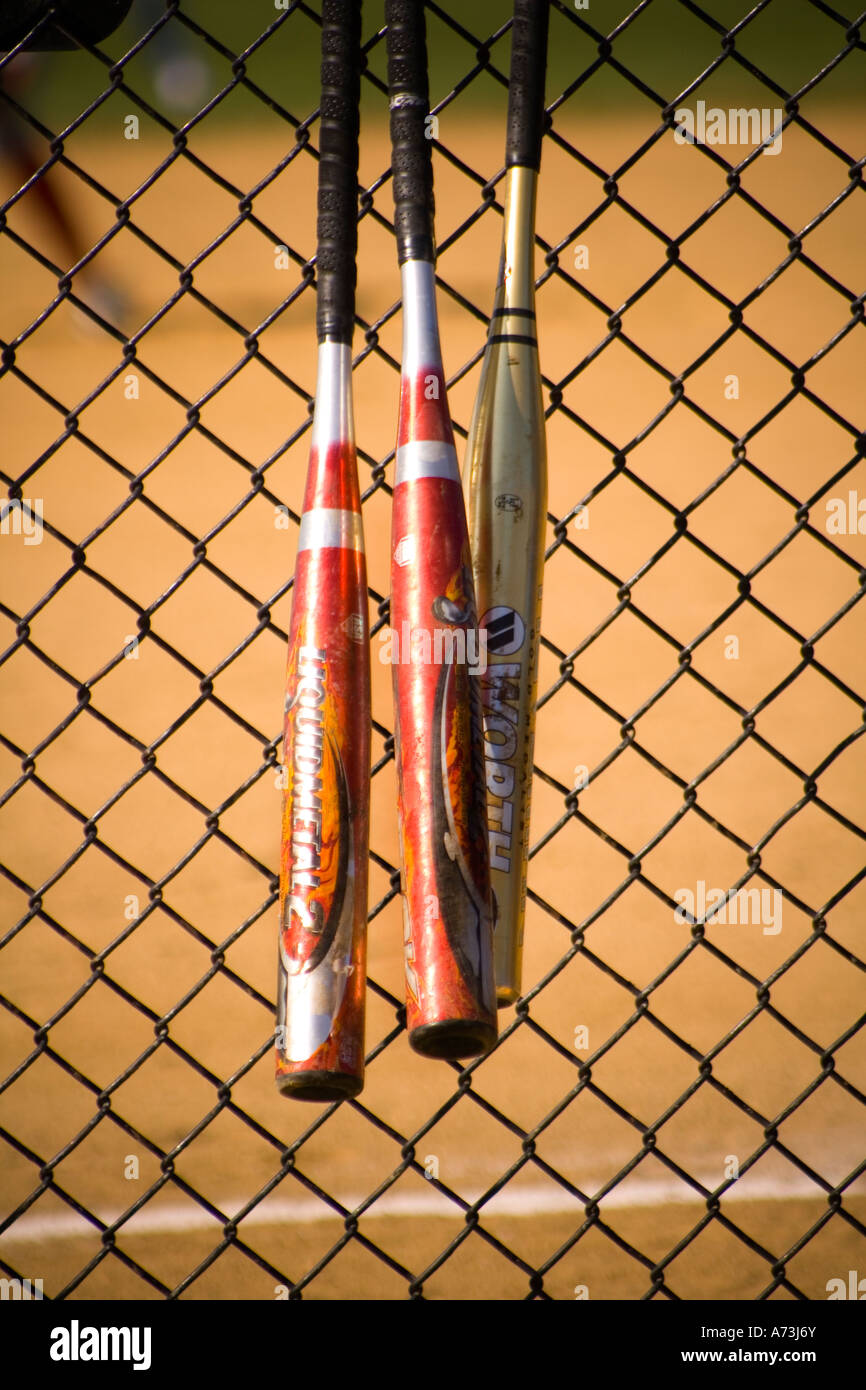three softball bats hanging on a fence Stock Photo - Alamy