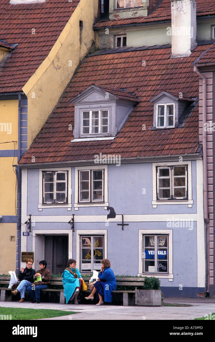 People talking while sitting on a park bench in historic Old Town Riga ...