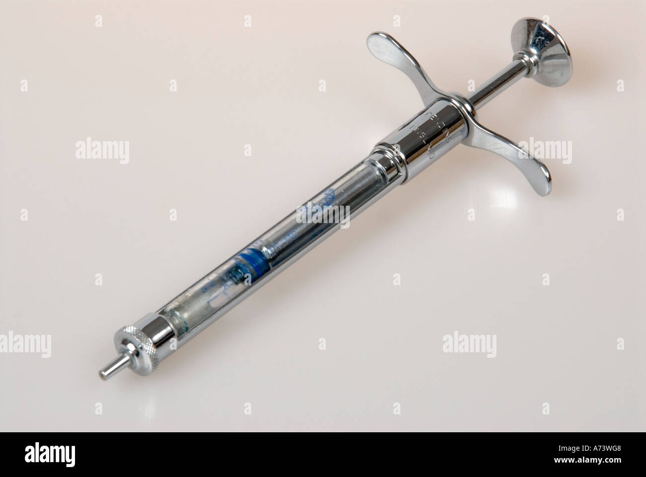 Glass and metal syringe against a white background Limited depth of ...