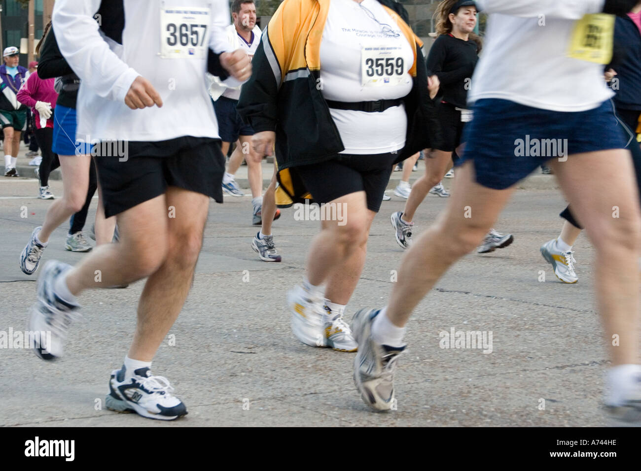Neck down view of runners in a race including an overweight woman Stock ...