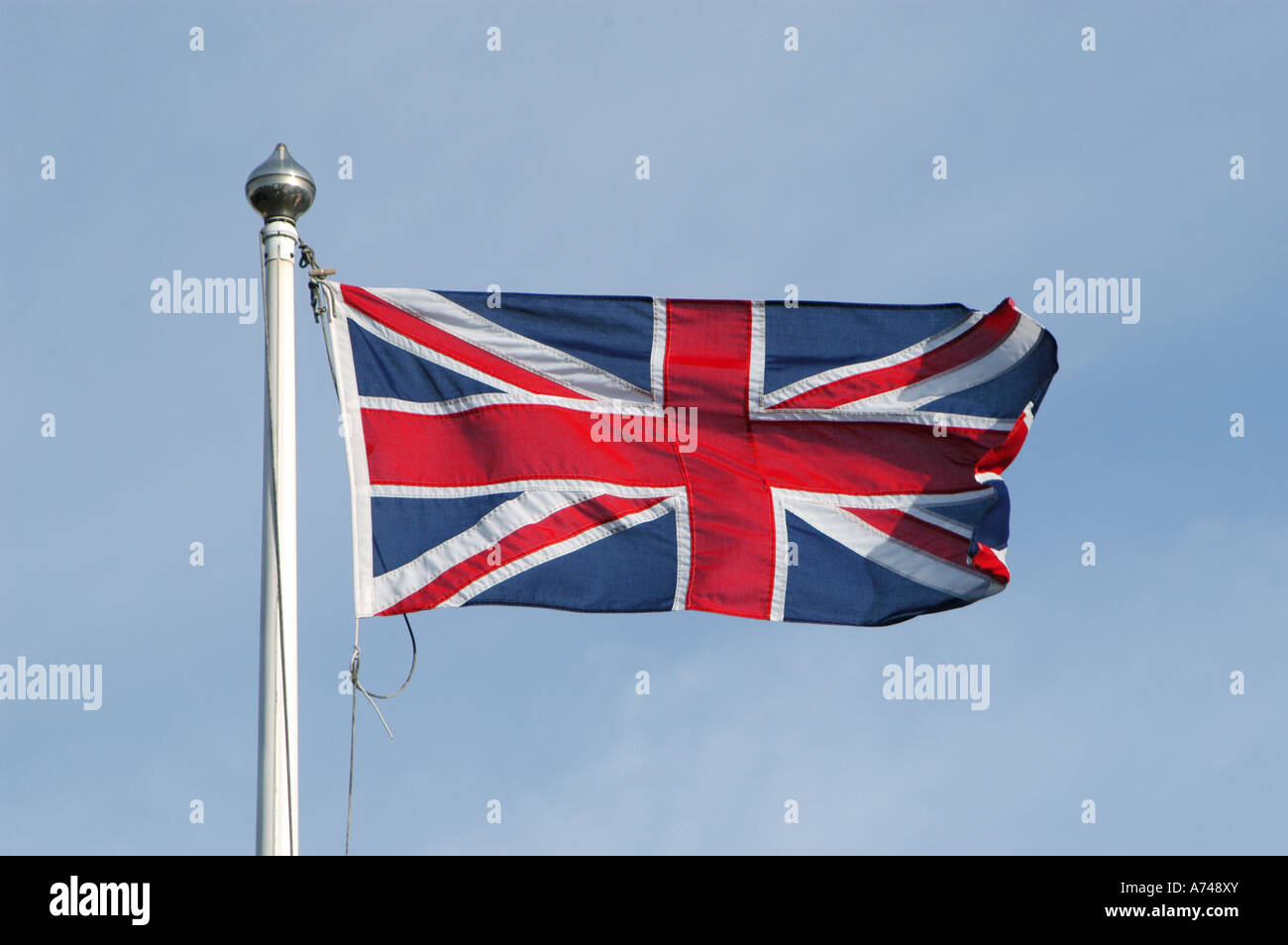 Union jack flag fluttering in the wind against a blue sky Stock Photo ...