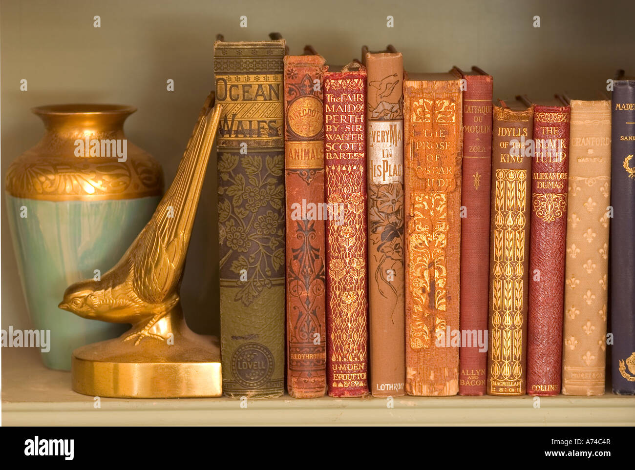 Antique books on a shelf with an antique vase and bookend Stock Photo ...