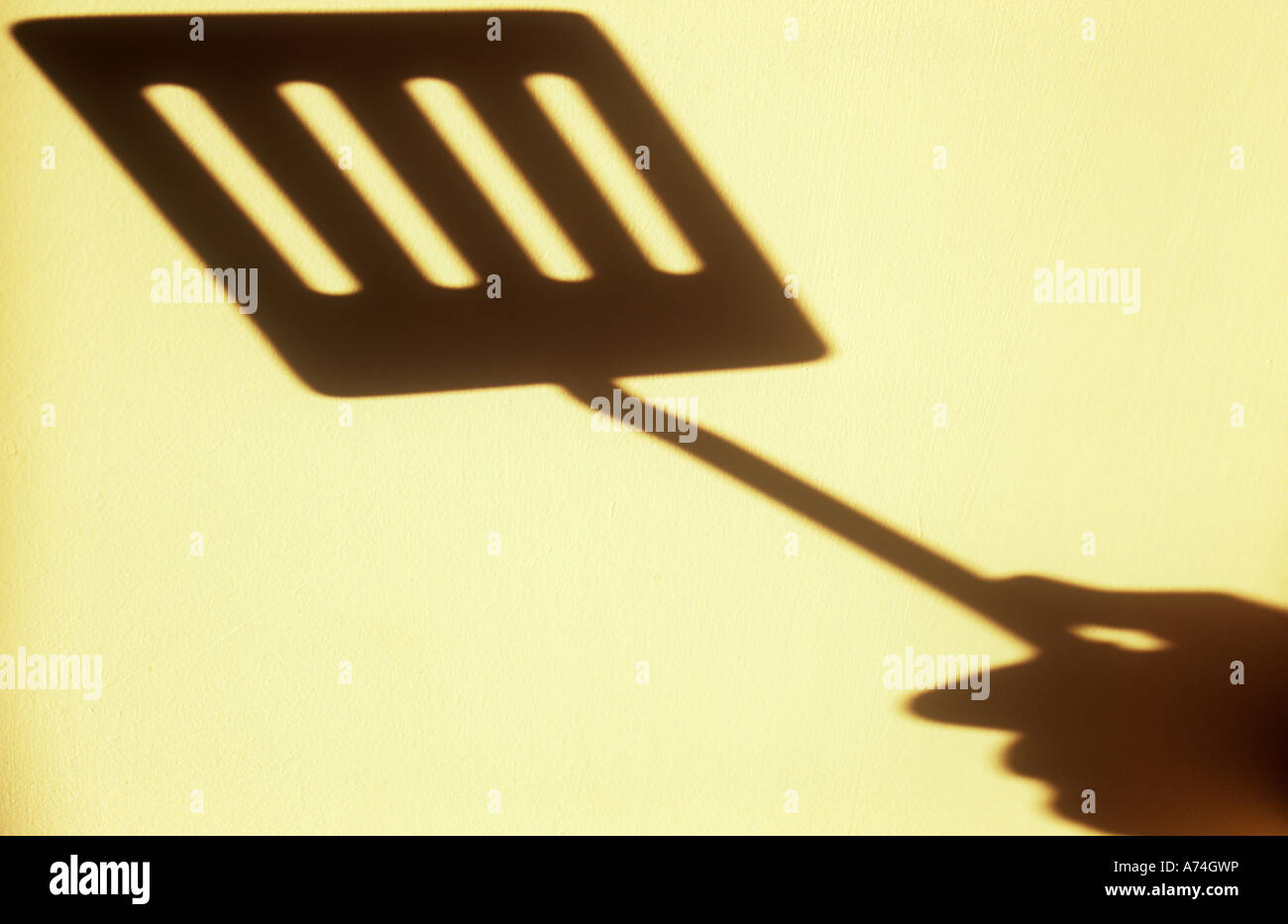 Close up of shadow on cream wall in warm light of hand holding a ...