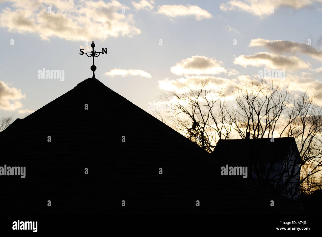 Silhouette of farm house with weathervane on roof indicating wind ...