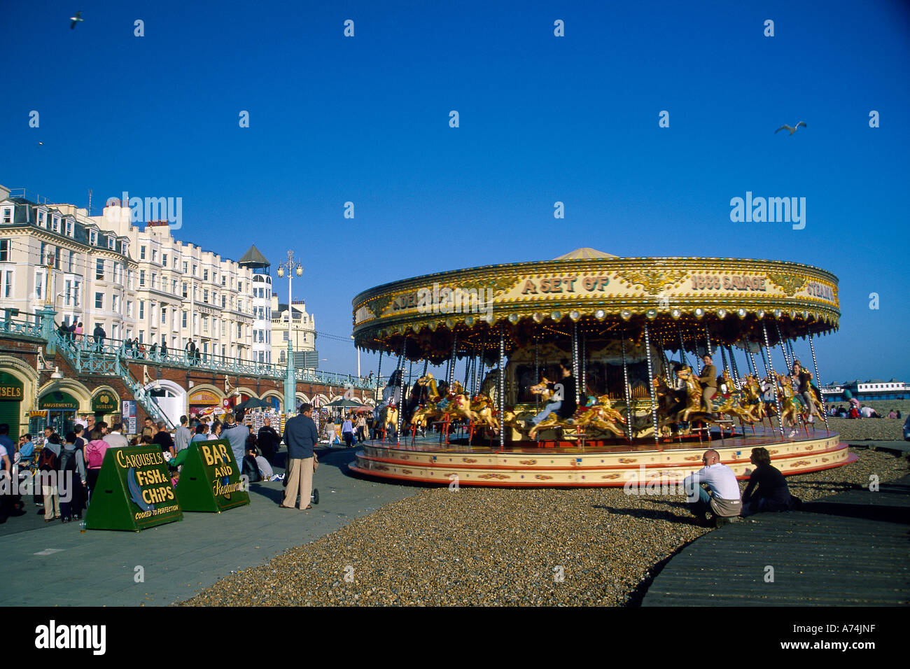Fairground carousel ride Gallopers Steam driven Pebble beach Shops fish ...