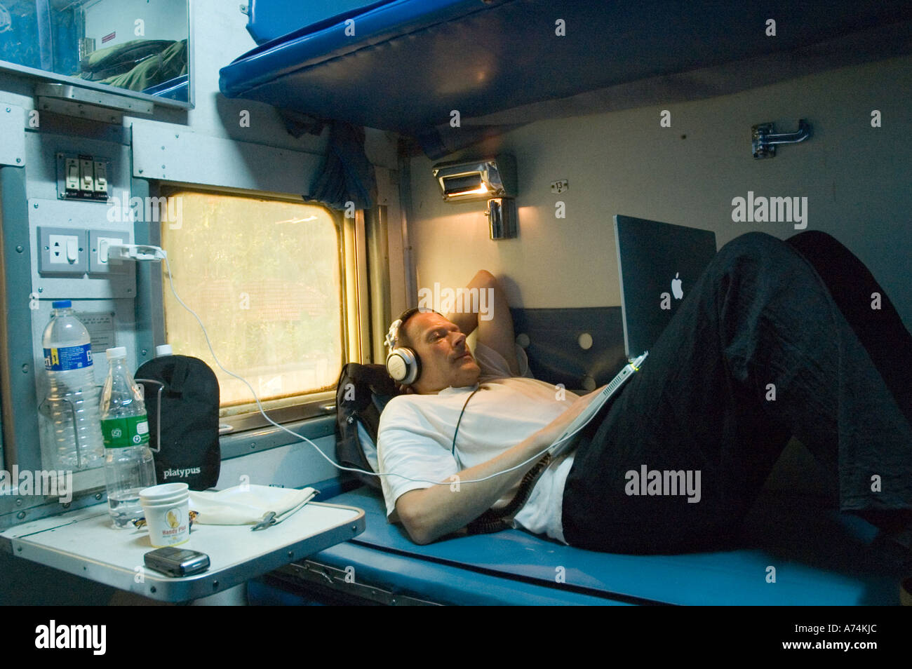 A man using a laptop computer on an air-conditioned Indian train Stock ...
