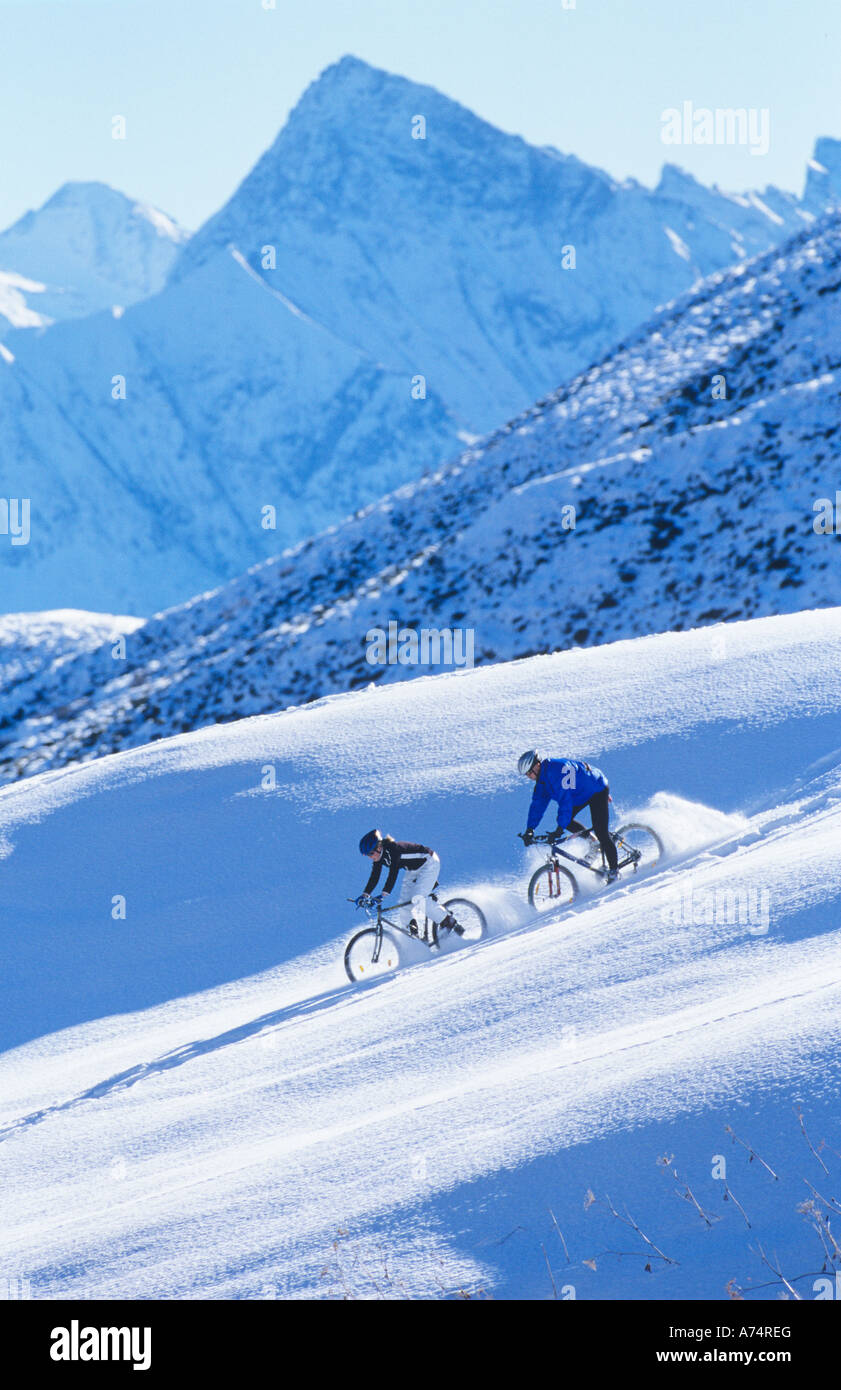 two people racing down snow covered mountain on bicycles Stock Photo ...