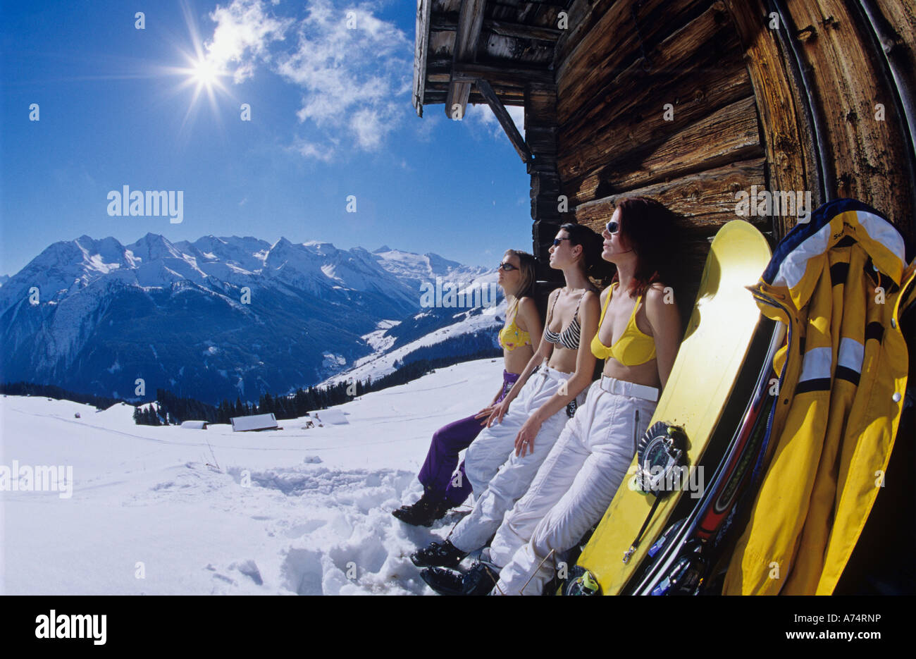 three young women in bikini tops sunbathing outside alpine hut Stock ...