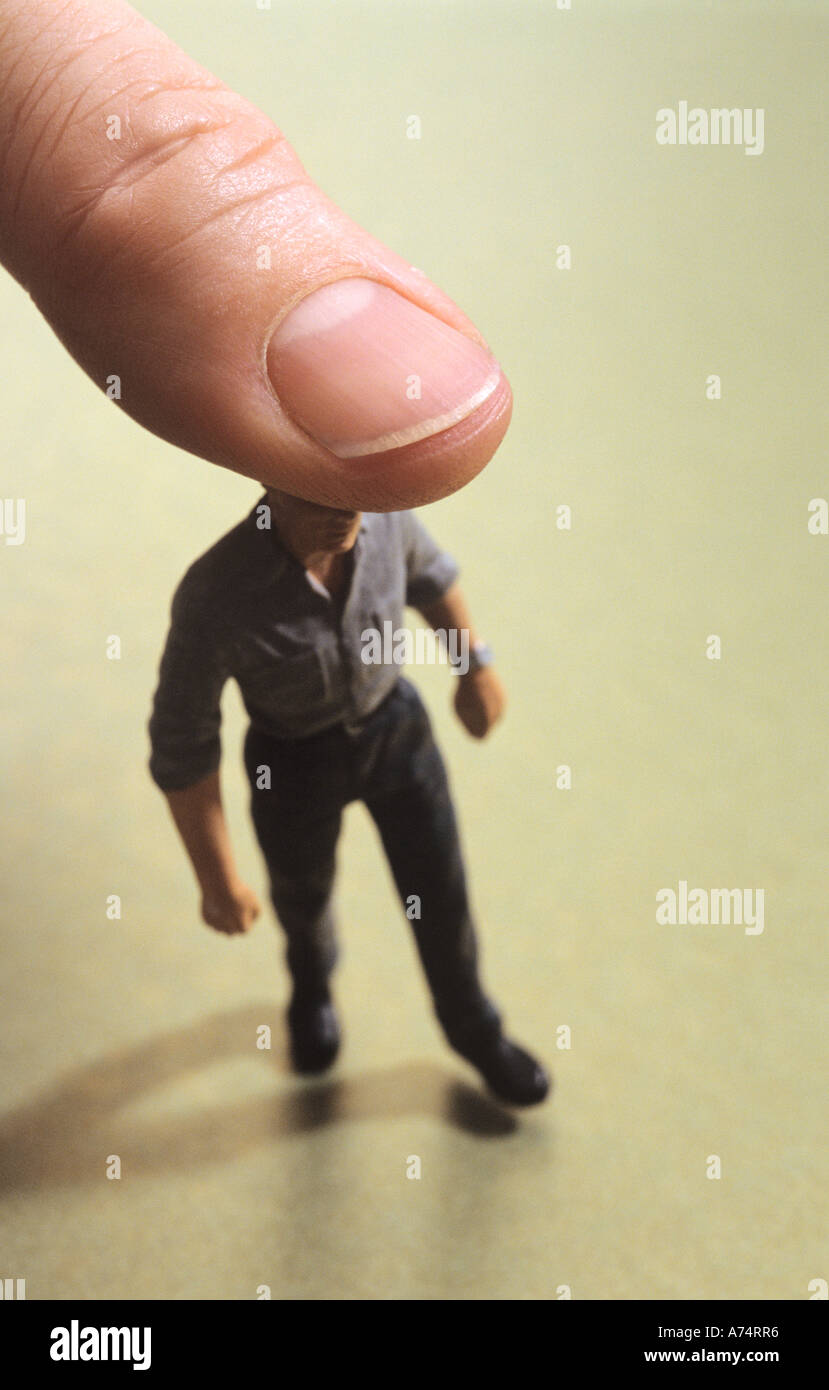 FIGURINE OF MAN UNDER MY THUMB Stock Photo - Alamy