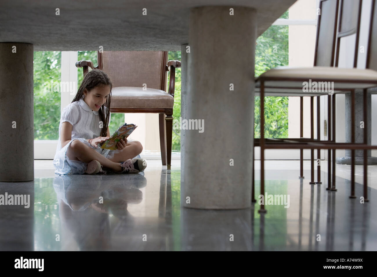 Young girl reading underneath table Stock Photo - Alamy