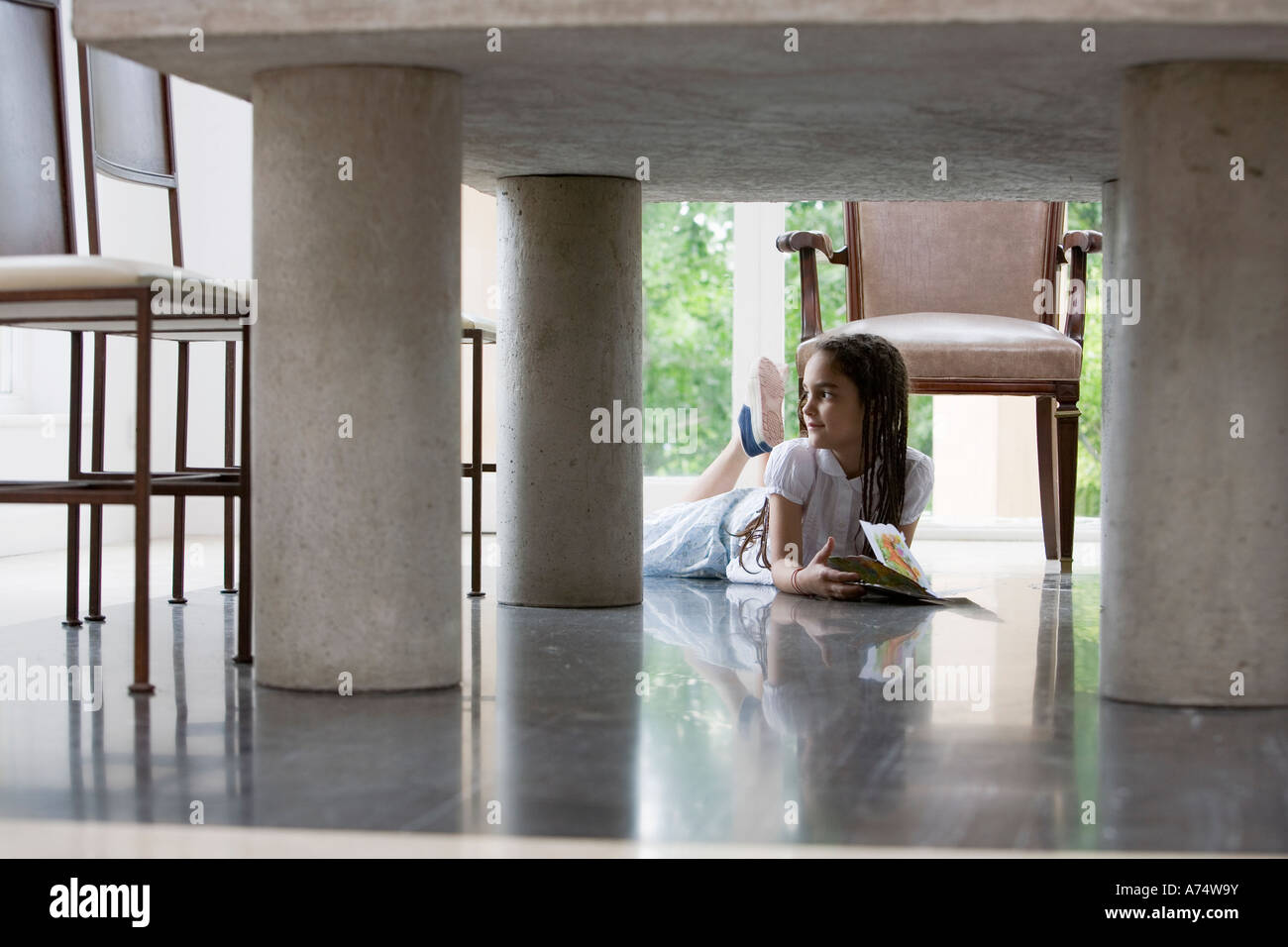 Young girl reading underneath table Stock Photo - Alamy