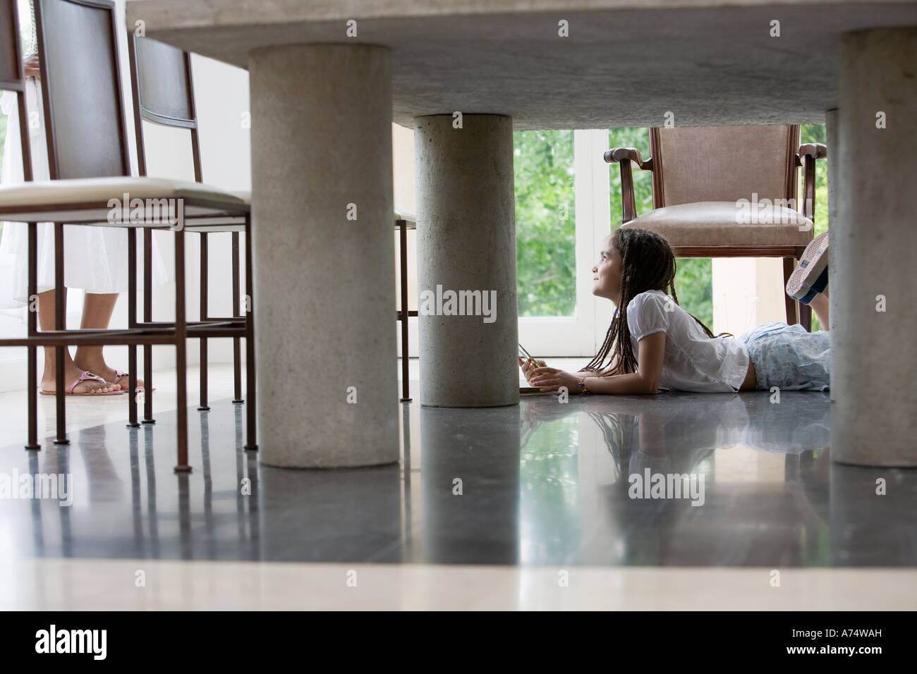 Young girl reading underneath table Stock Photo - Alamy