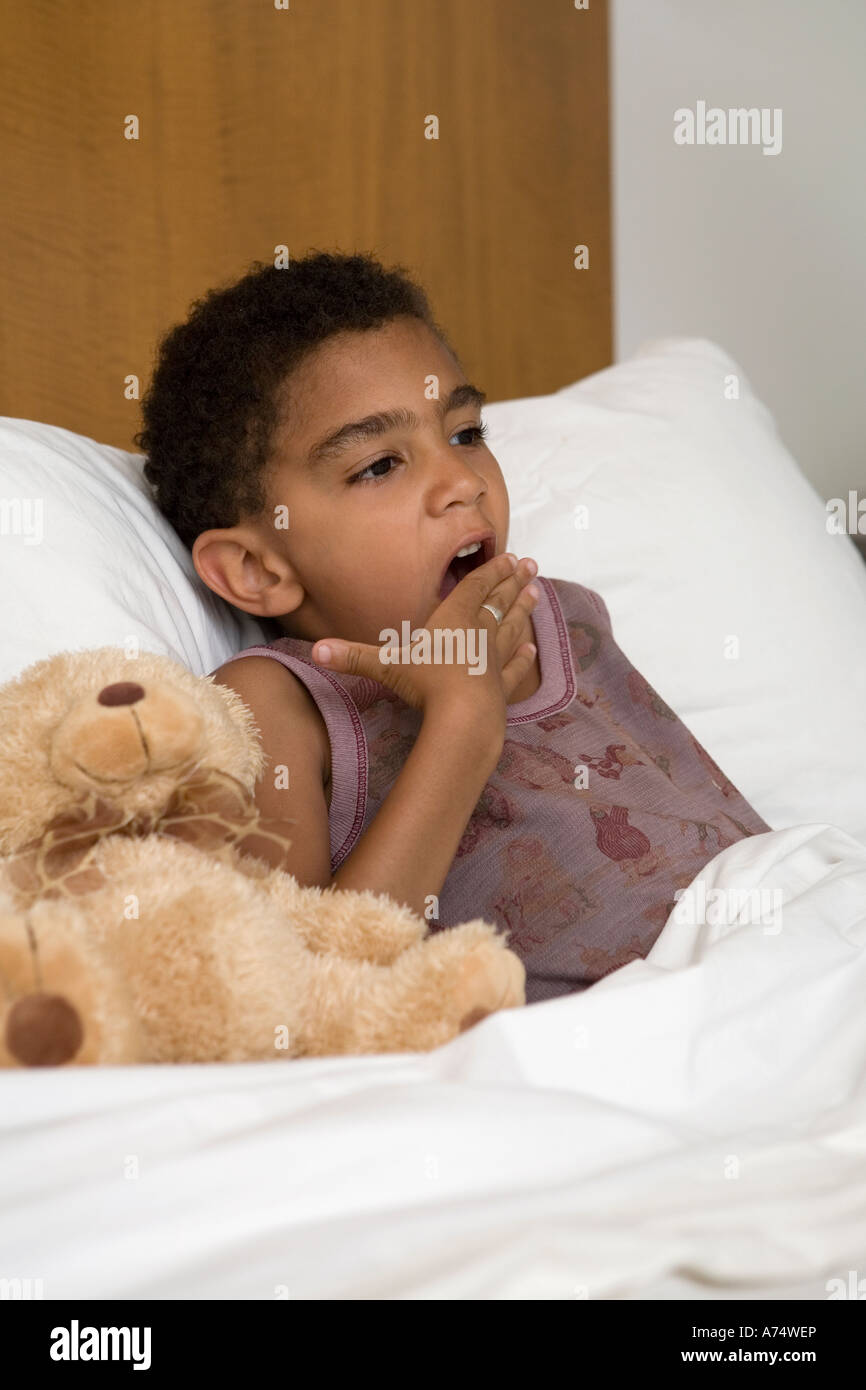 Young boy yawning in bed Stock Photo - Alamy