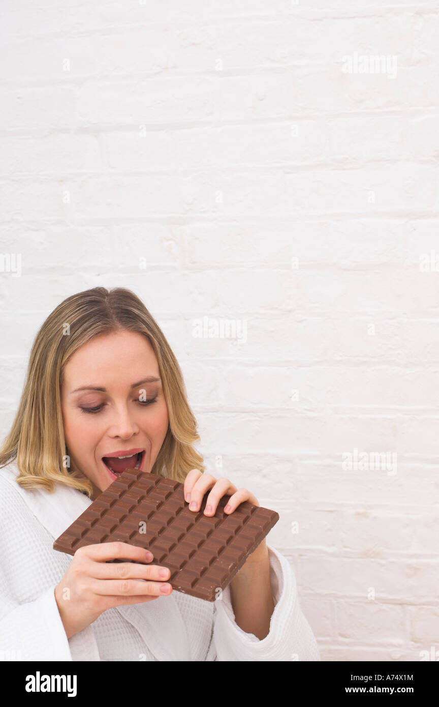young woman biting into giant chocolate bar Stock Photo - Alamy
