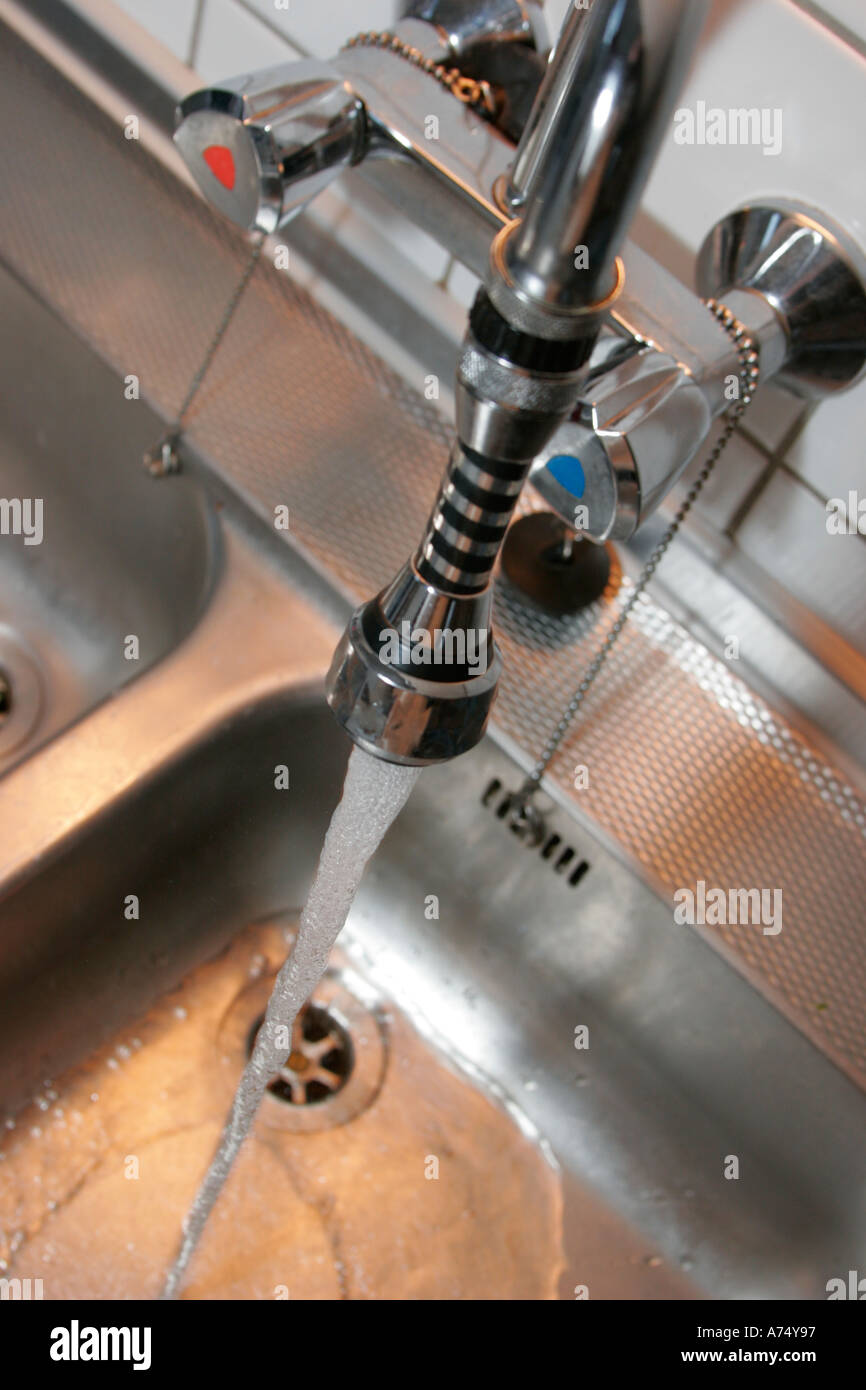 Running water in a dual sink at a kitchen with cold and hot water tap ...