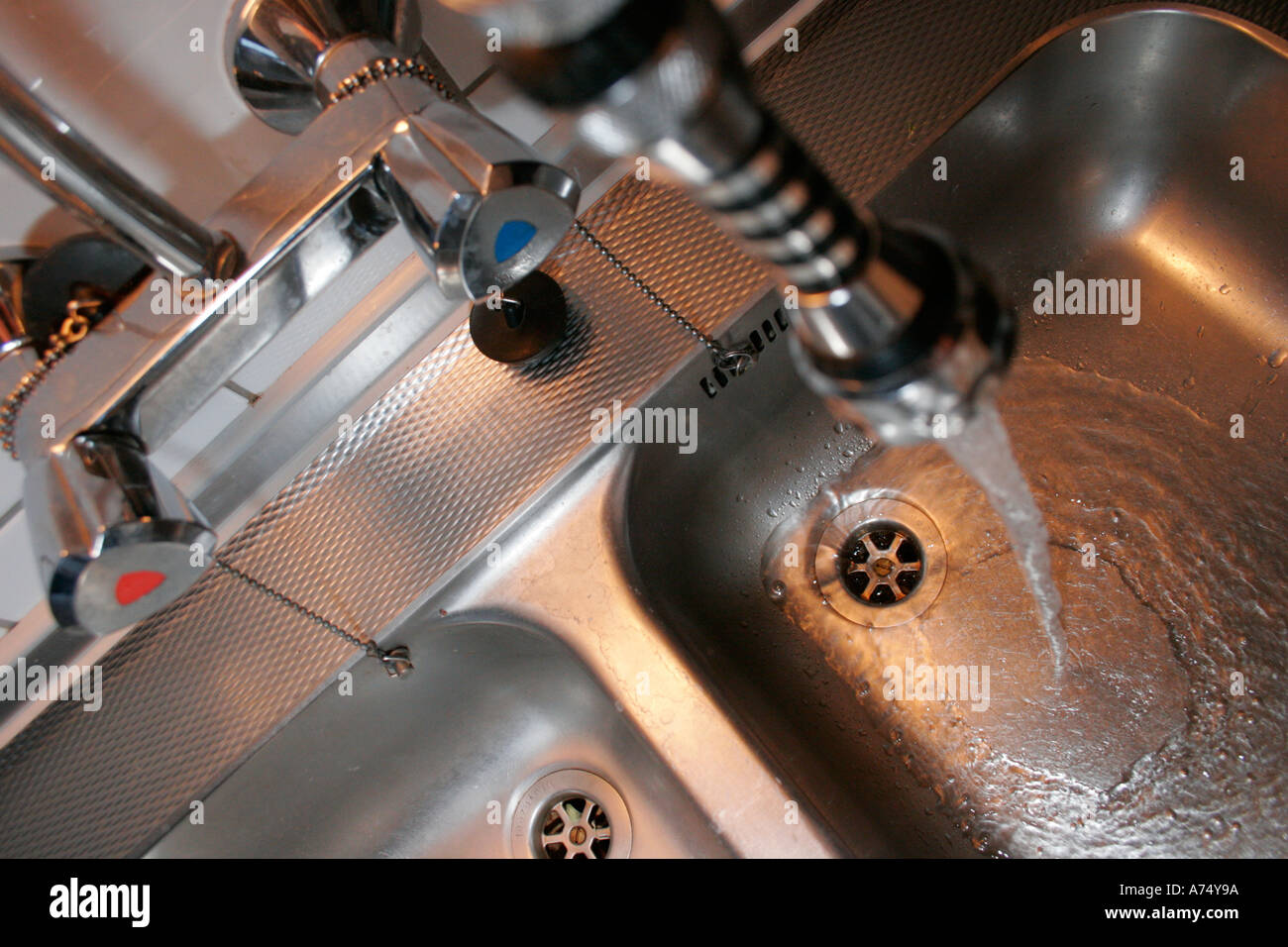 Running water in a dual sink at a kitchen with cold and hot water tap ...