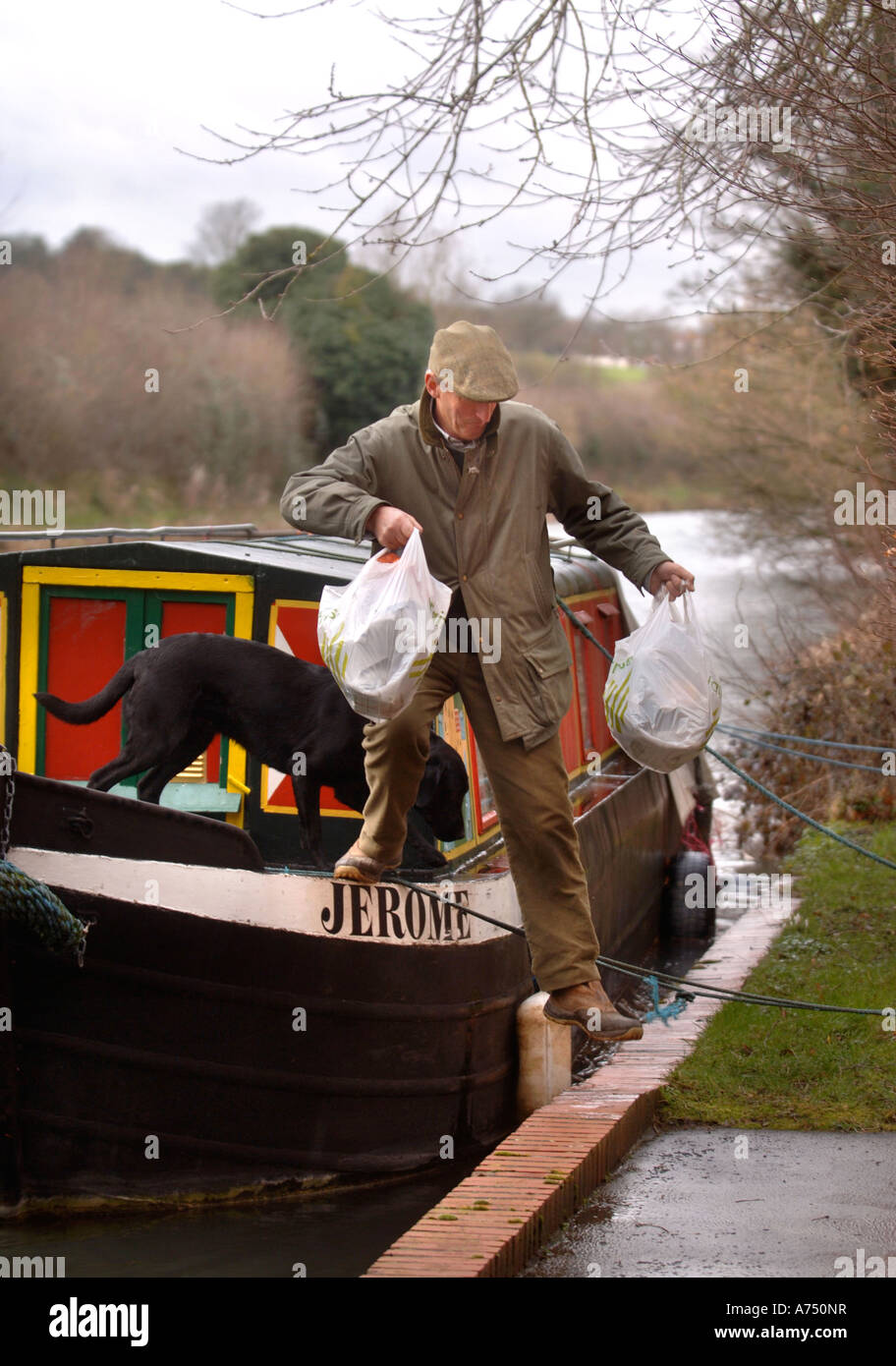 A MAN STEPS OFF A CANAL BARGE MOORED OUTSIDE A MILL ON THE KENNET AND ...
