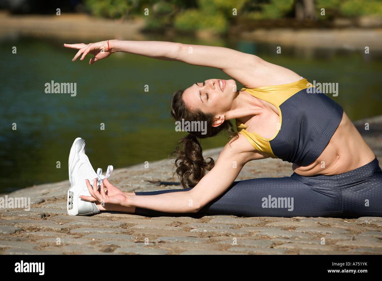Woman stretching by pond Stock Photo - Alamy