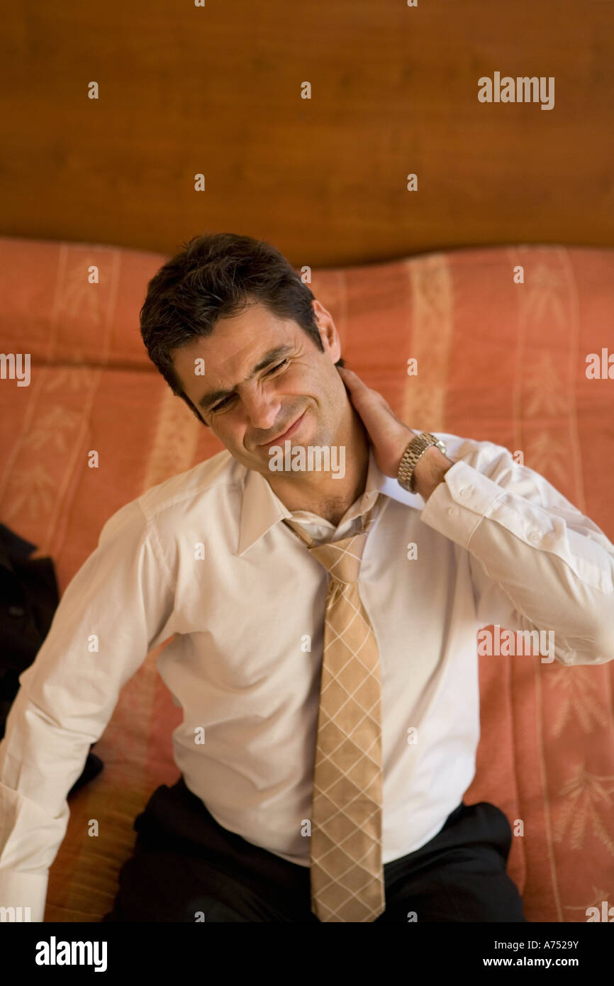 Businessman rubbing his neck in hotel room Stock Photo - Alamy