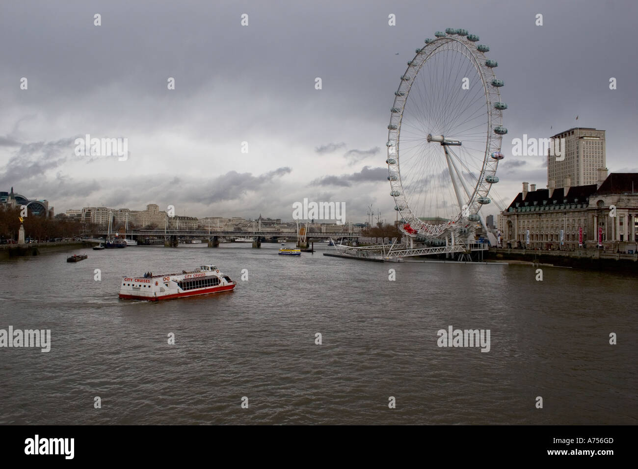 The London eye on a dull grey day with a view of the river Thames and ...