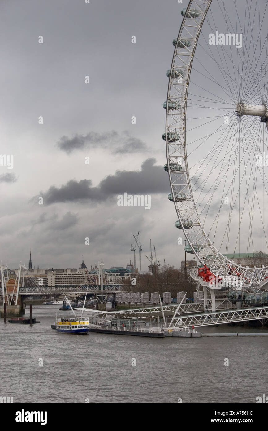 The London eye on a dull grey day with a view of the river Thames and ...