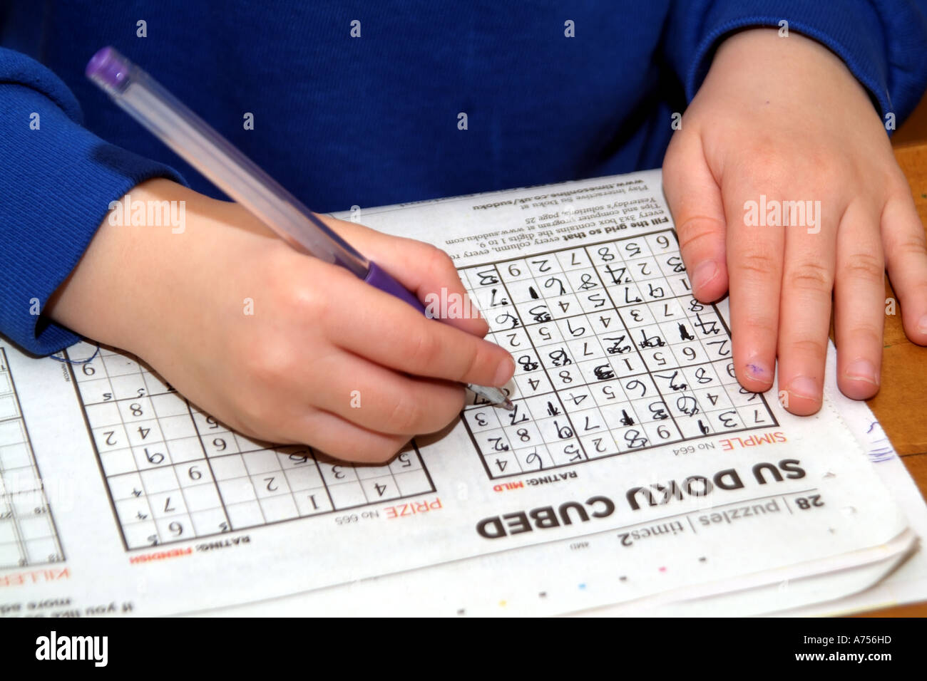 Su Doku sudoku Childs hands completing and solving this popular puzzle ...
