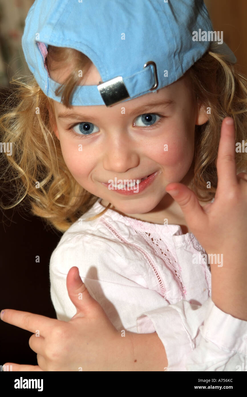 Little attractive girl wearing a baseball cap play acting a cool dude ...