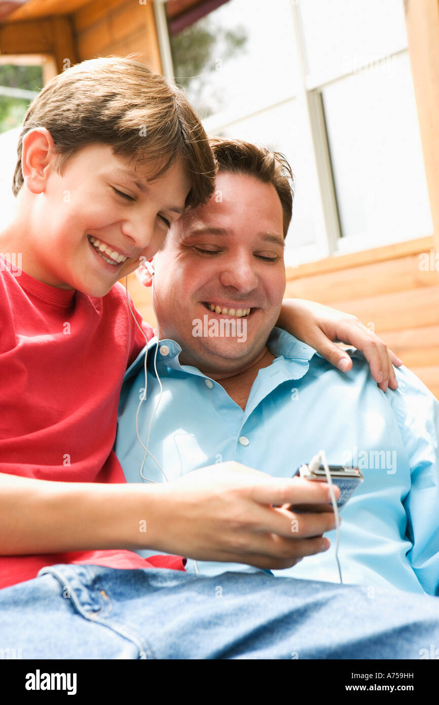 Young man and son listening to mp3 player Stock Photo - Alamy