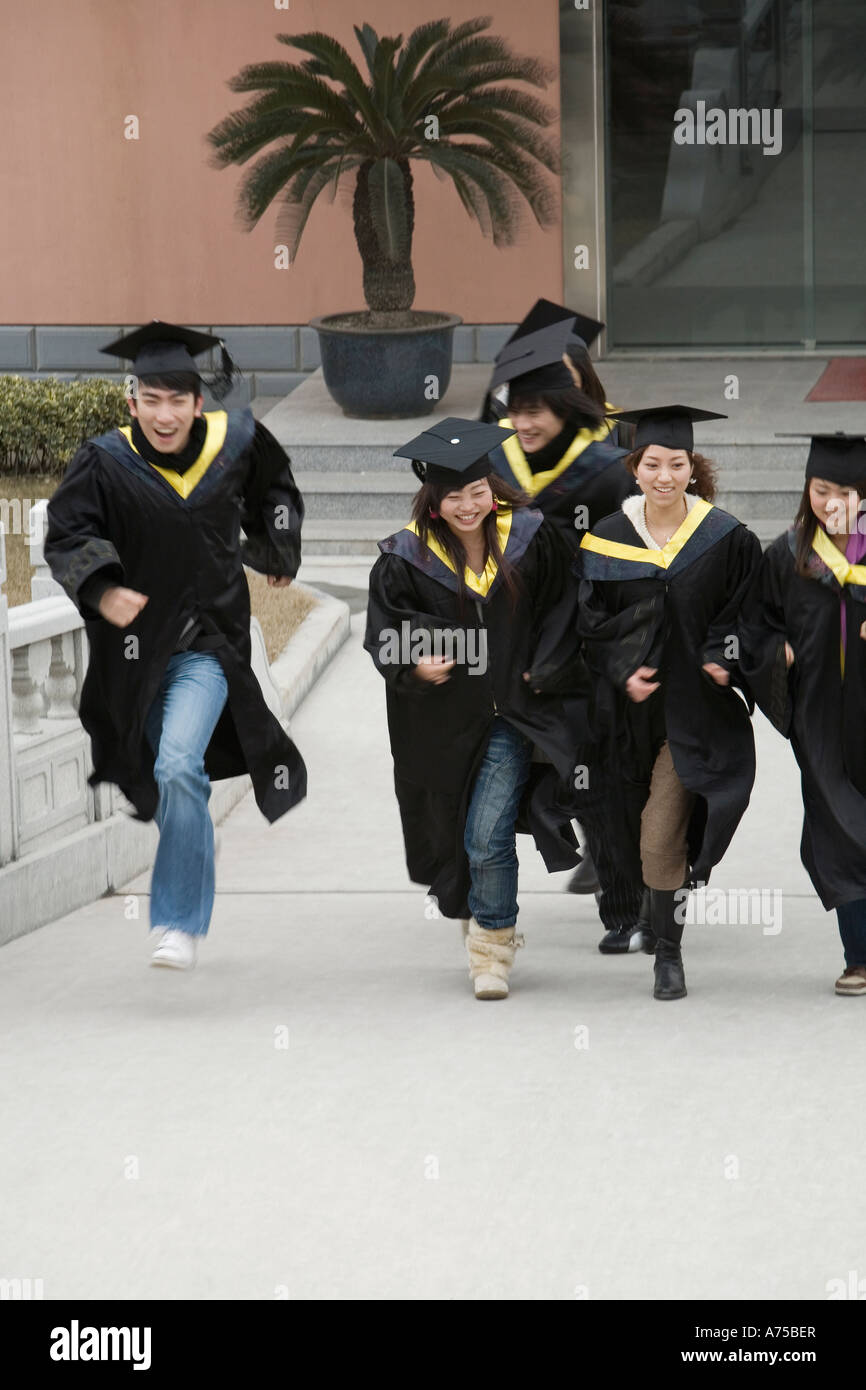 Students in graduation robes running Stock Photo - Alamy