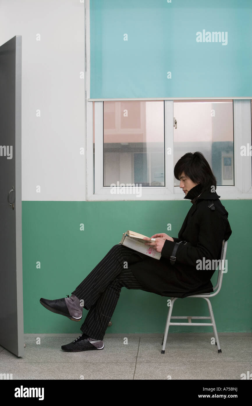 Man reading book in empty room Stock Photo - Alamy