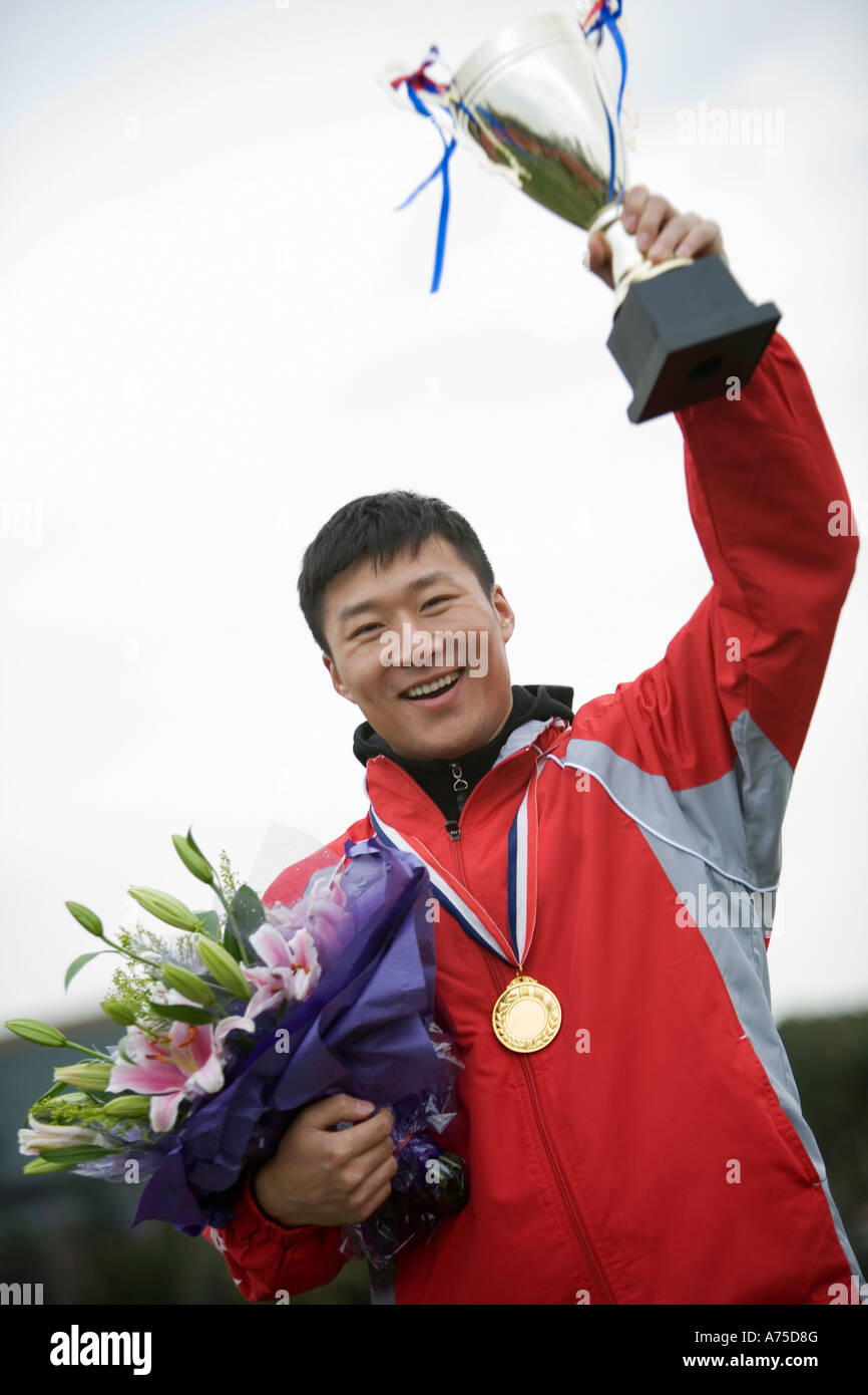 Male athlete wearing a gold medal and waving trophy Stock Photo - Alamy