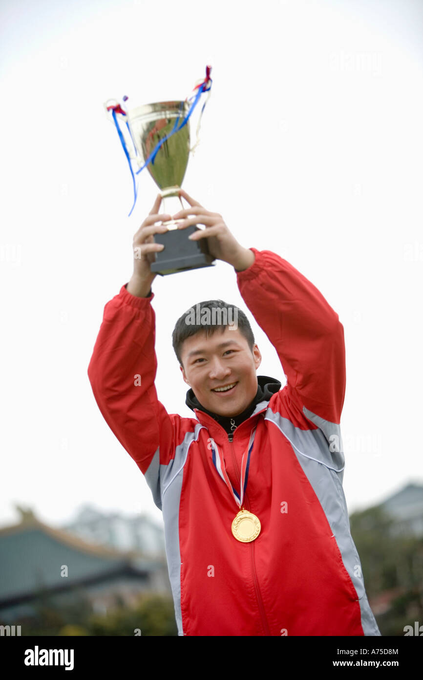 Male athlete wearing a gold medal and waving trophy Stock Photo - Alamy