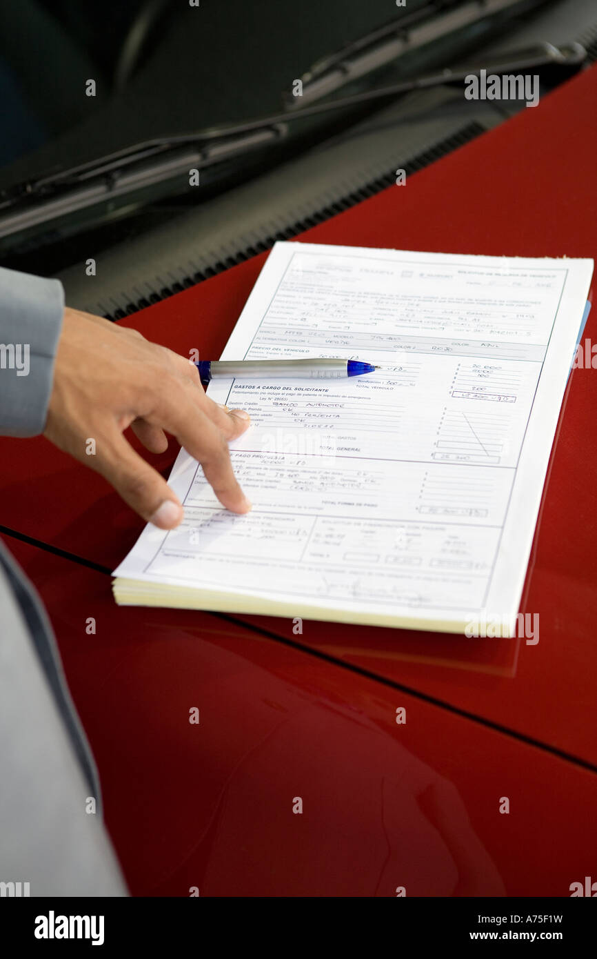 Salesman holding contract in car dealership Stock Photo - Alamy