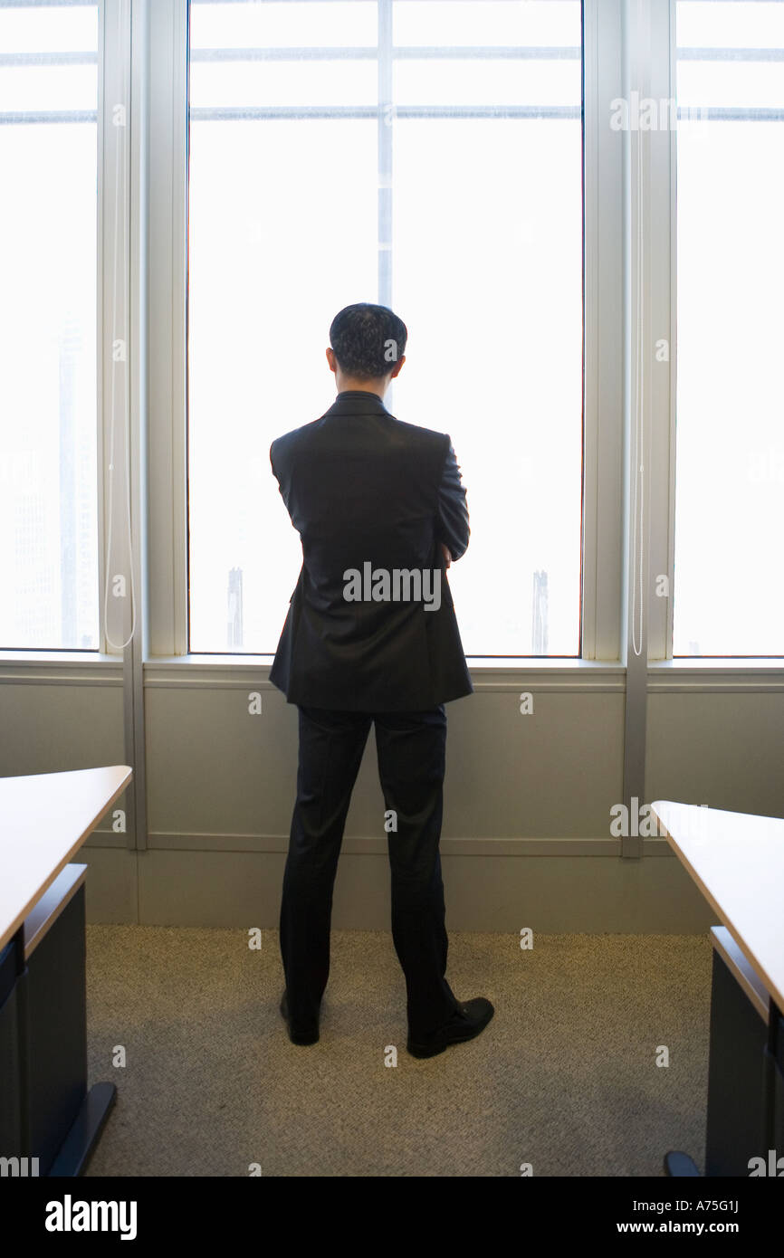 Businessman looking out office window Stock Photo - Alamy