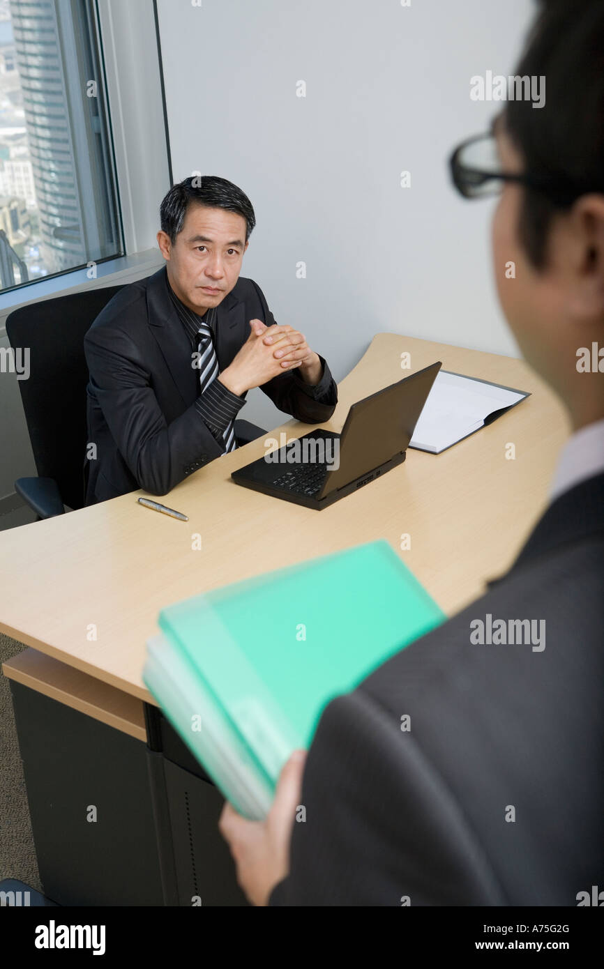 Businessman talking to co-worker in office Stock Photo - Alamy