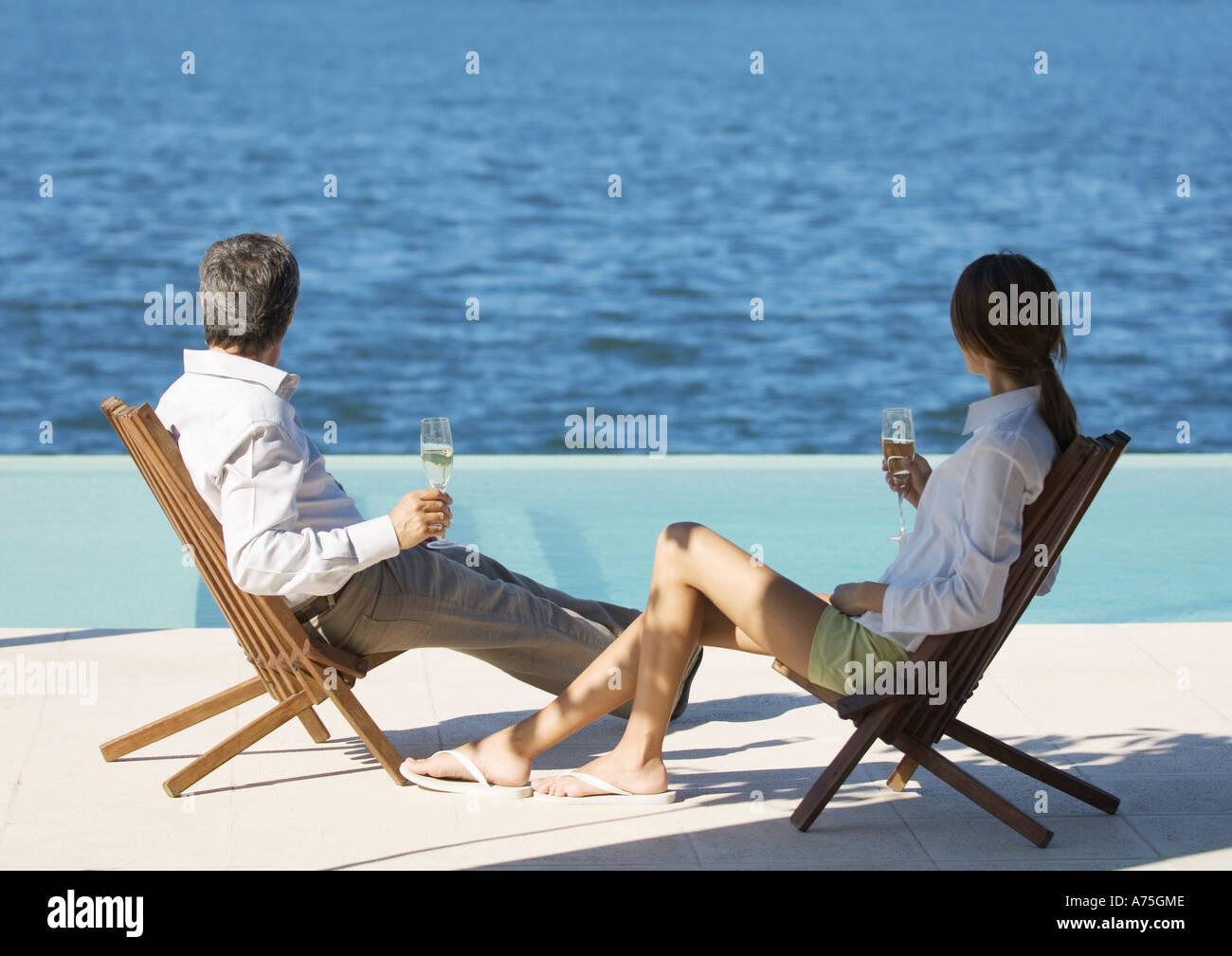 Couple sitting with glasses of champagne, overlooking water Stock Photo ...